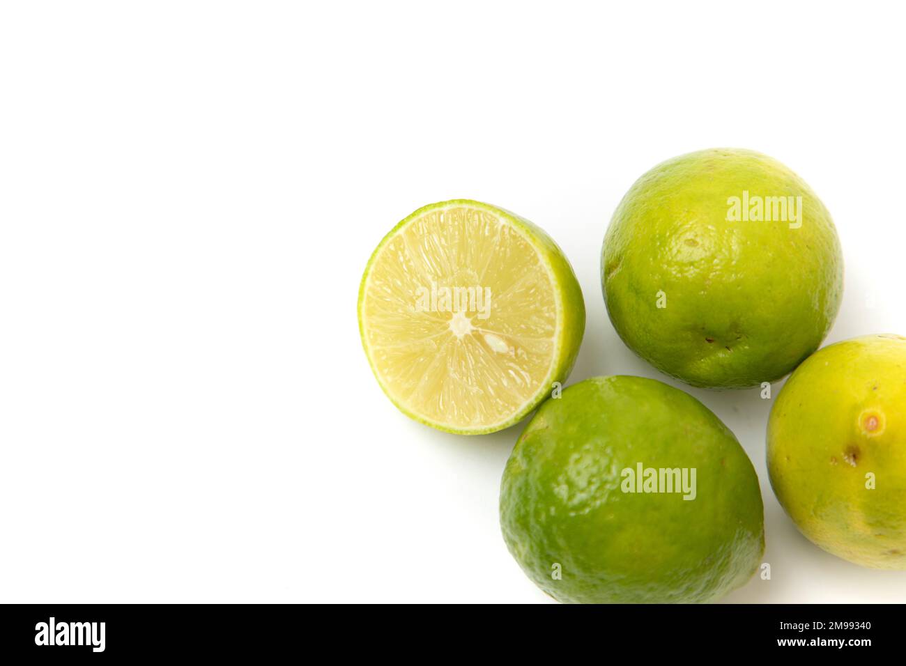 A group of stacked lemons, and a lemon cut in half, with a white ...