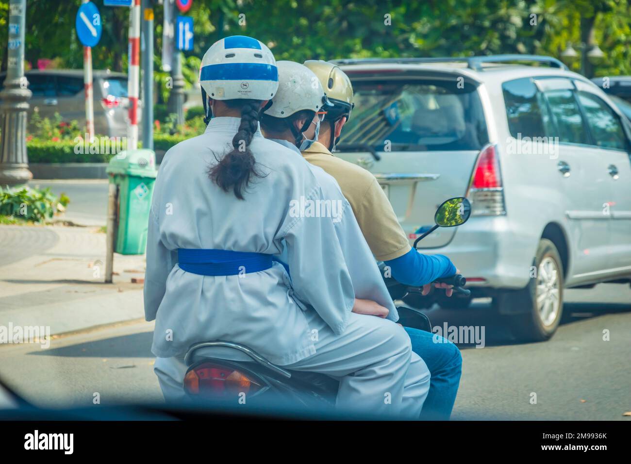 back of a girl in kimono with braid in helmet on a moped as a passenger ...