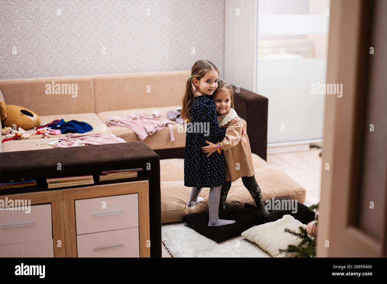 Two sisters at home on the sofa hugging tightly together Stock Photo ...