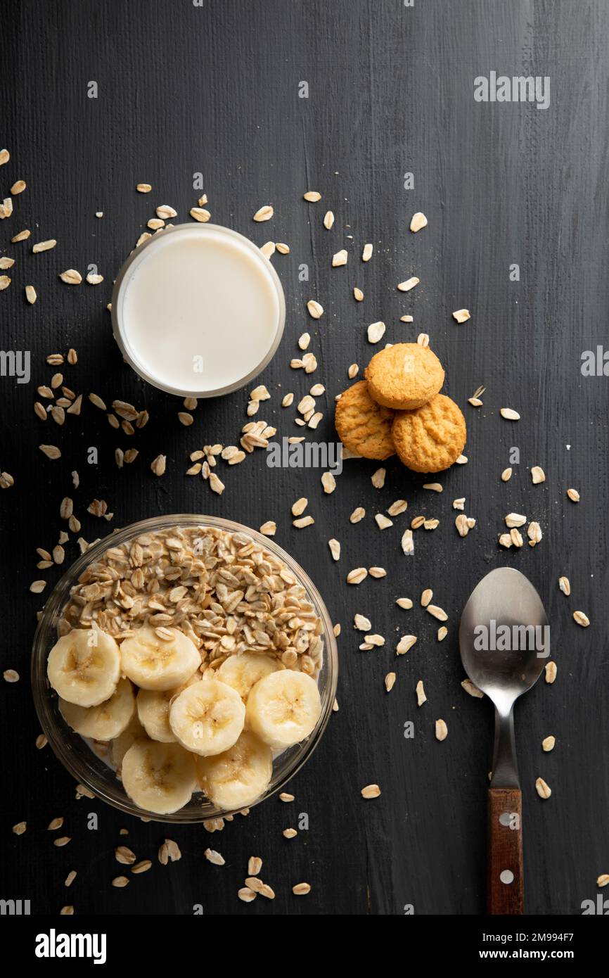 vertical image of a bowl with oatmeal and banana accompanied by a glass ...