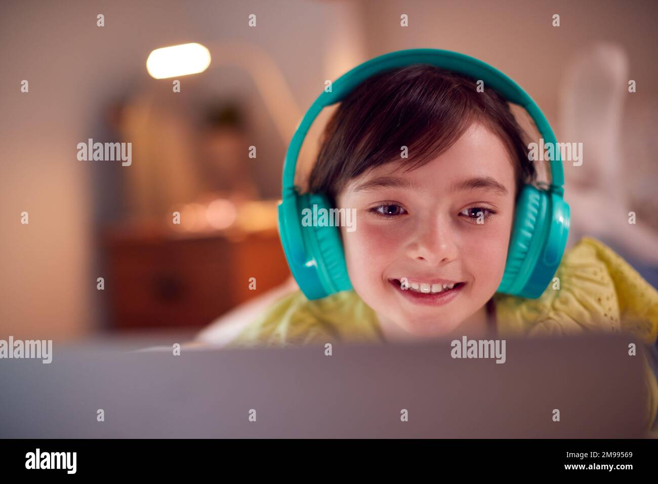 Girl In Bedroom At Night Lying On Bed Wearing Wireless Headphones Using ...