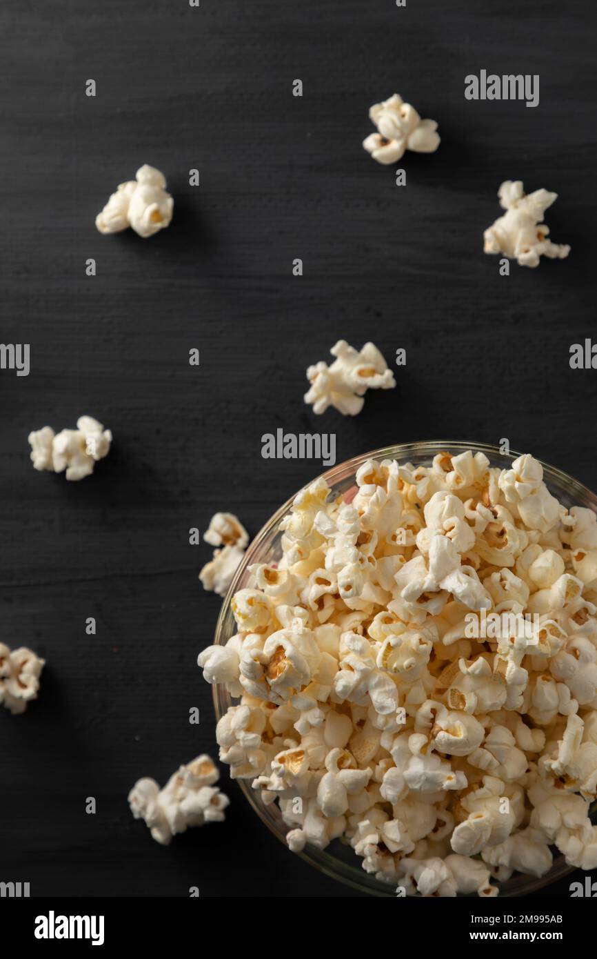 vertical image of a bowl of popcorn on a black wooden base, and expacio ...