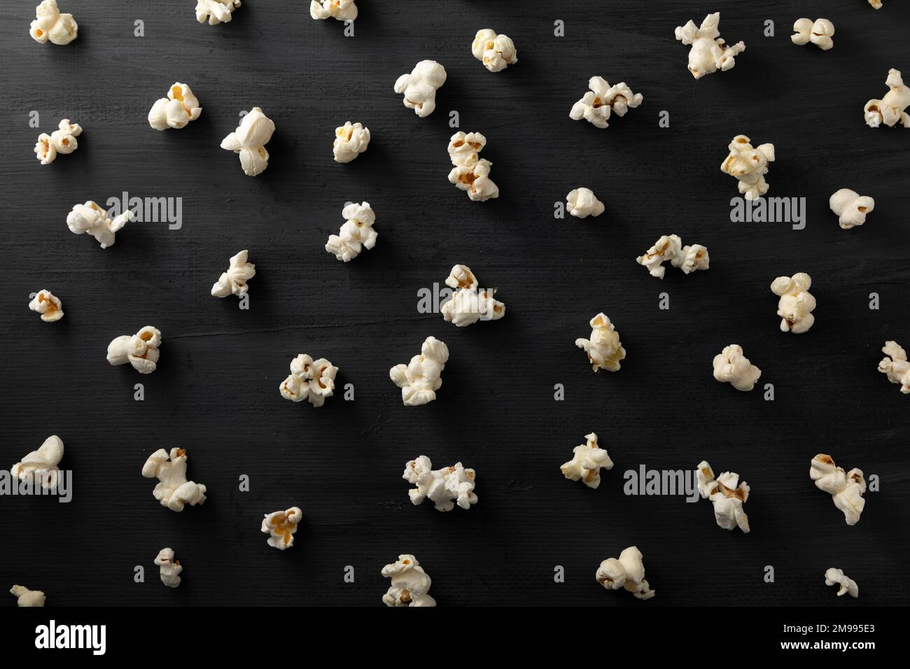 Top view of a group of popcorn, arranged in a pattern, on a black ...
