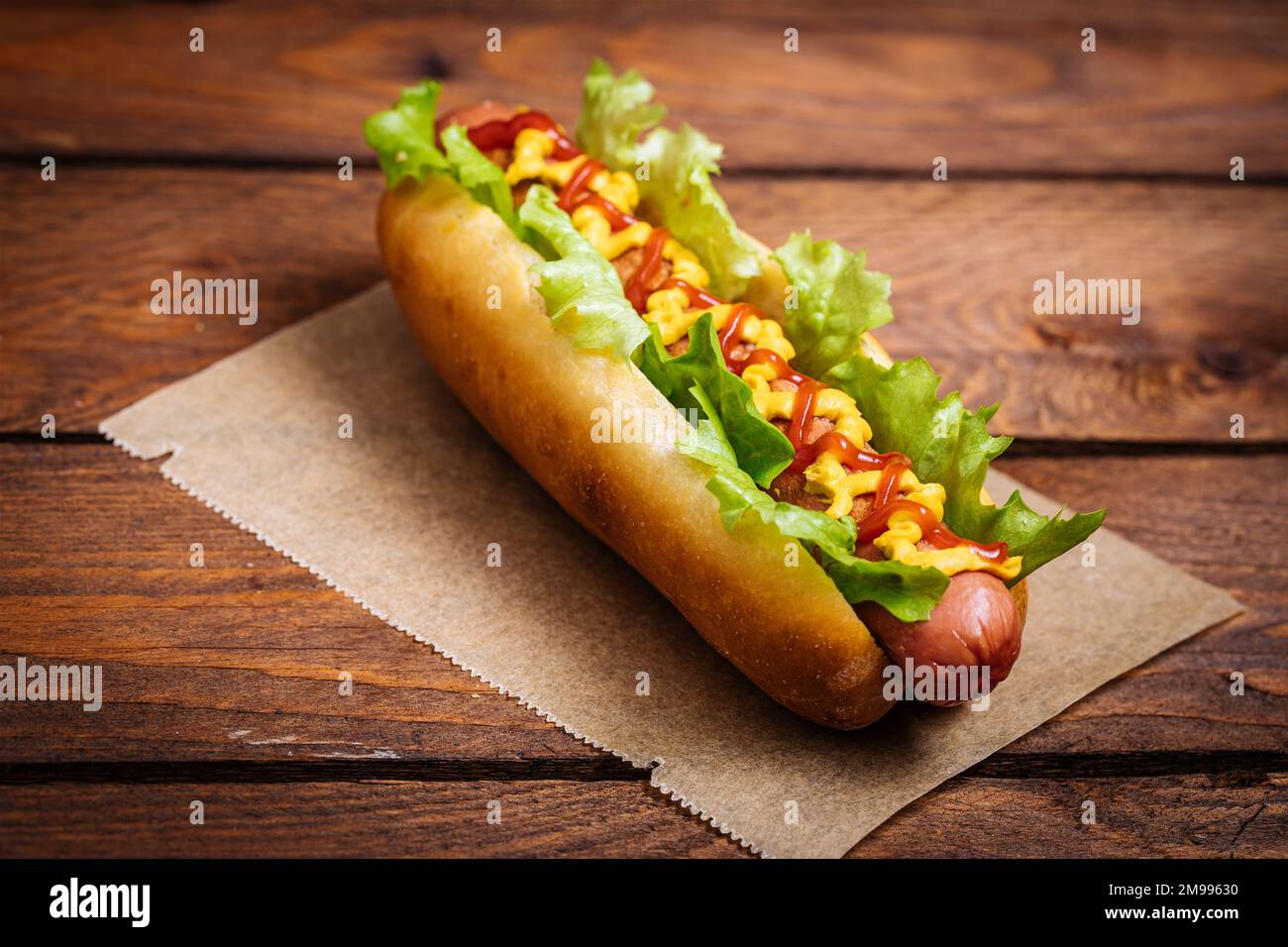 Hot dog with mustard, ketchup and green salad in bun, served with ...