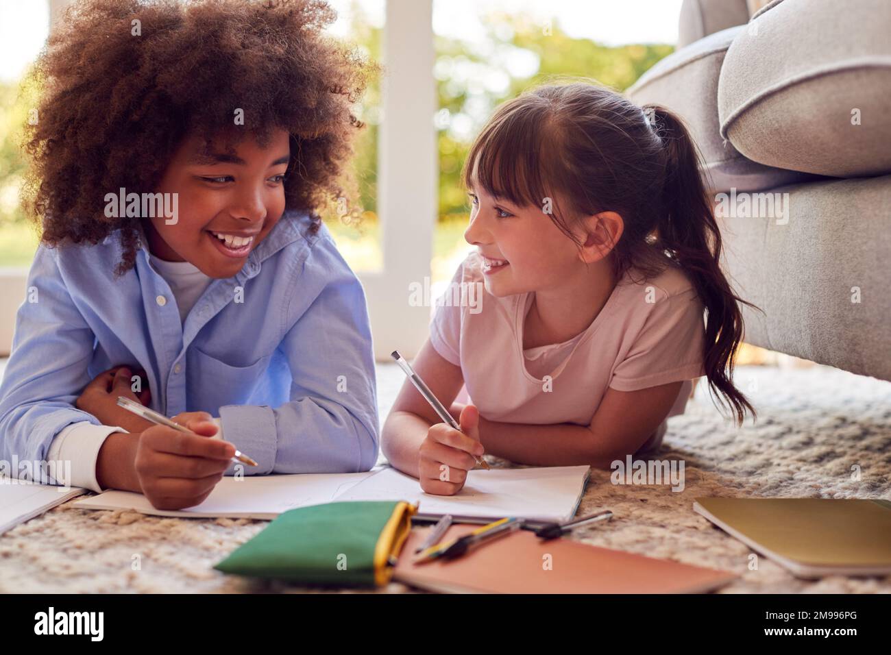 Boy And Girl Lying On Rug In Lounge At Home Doing School Homework ...