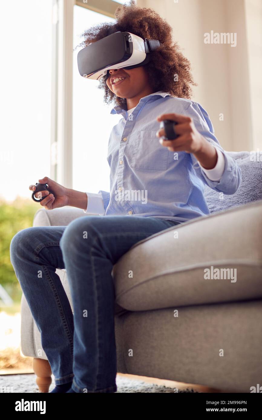 Boy Sitting On Sofa In Lounge Wearing VR Headset Playing Game Stock ...