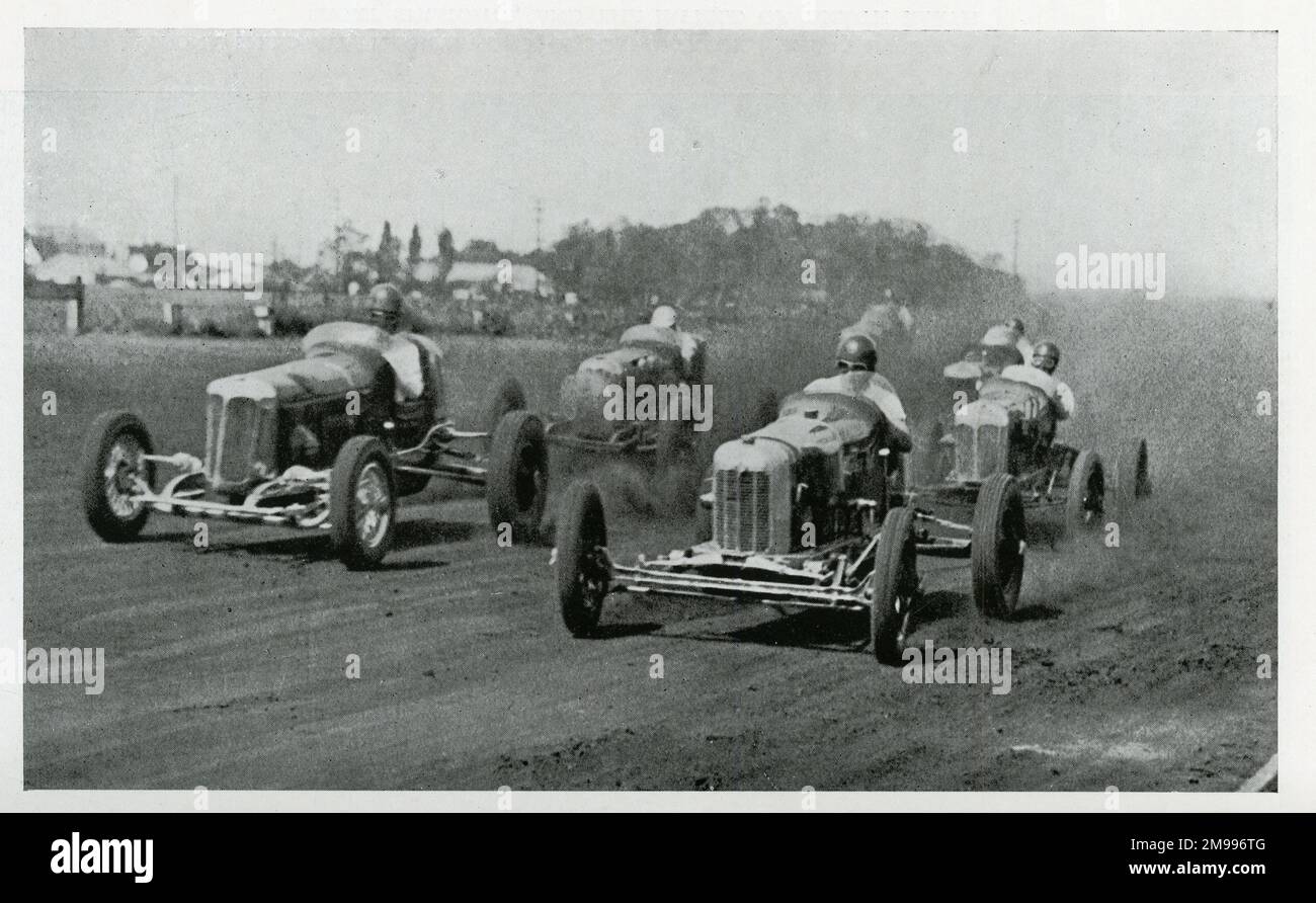 A group of cars halfway round the track in the opening lap of an ...