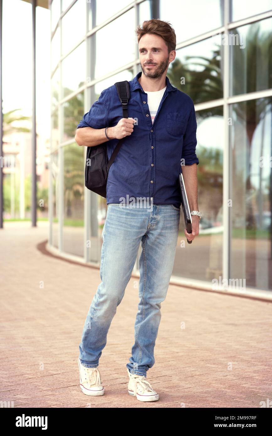 University student walking by the campus with laptop in hand Stock ...