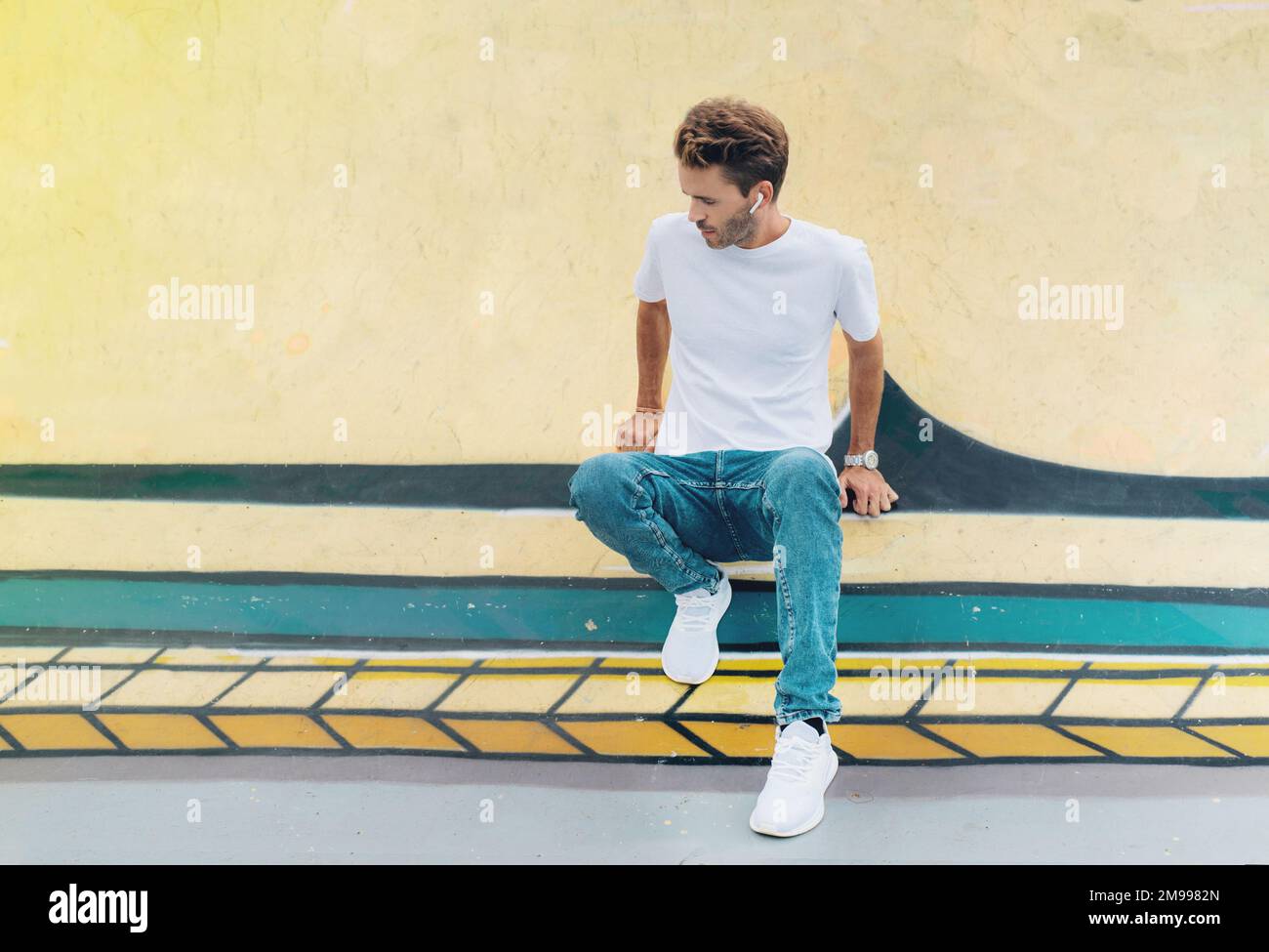 Young handsome guy is standing on a graffiti wall background. Man is ...