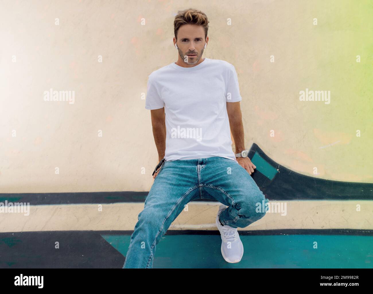 Young handsome guy is standing on a graffiti wall background. Man is ...