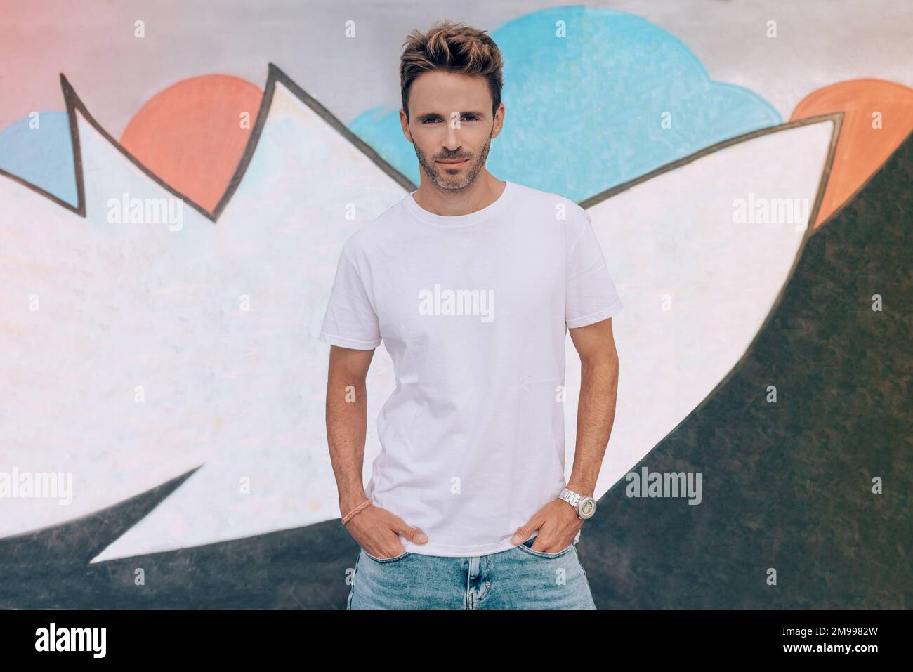 Young handsome guy is standing on a graffiti wall background. Man is ...