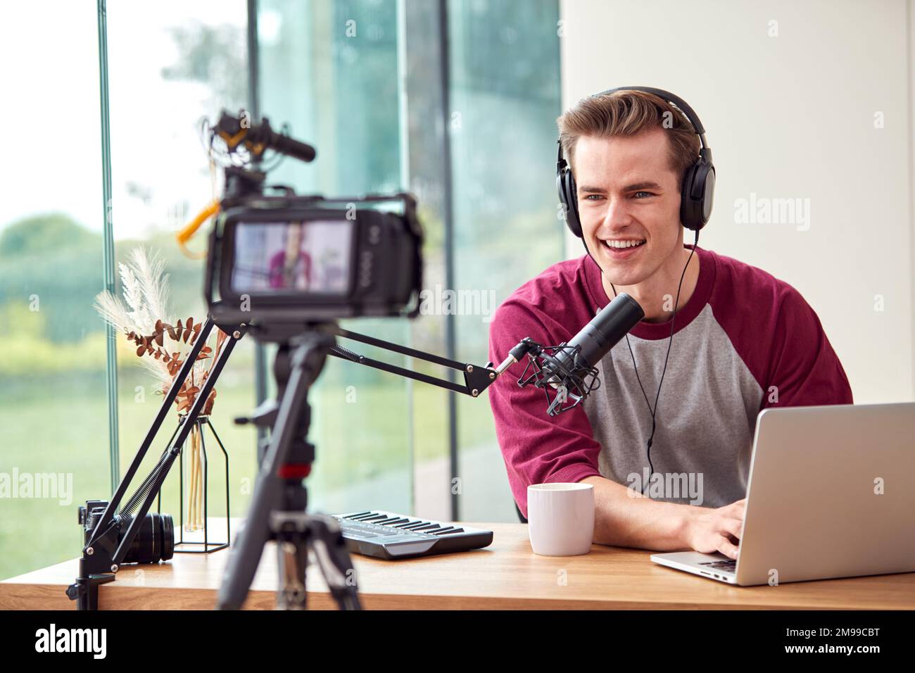 Male Vlogger With Laptop Recording Video At Home With Camera Stock ...