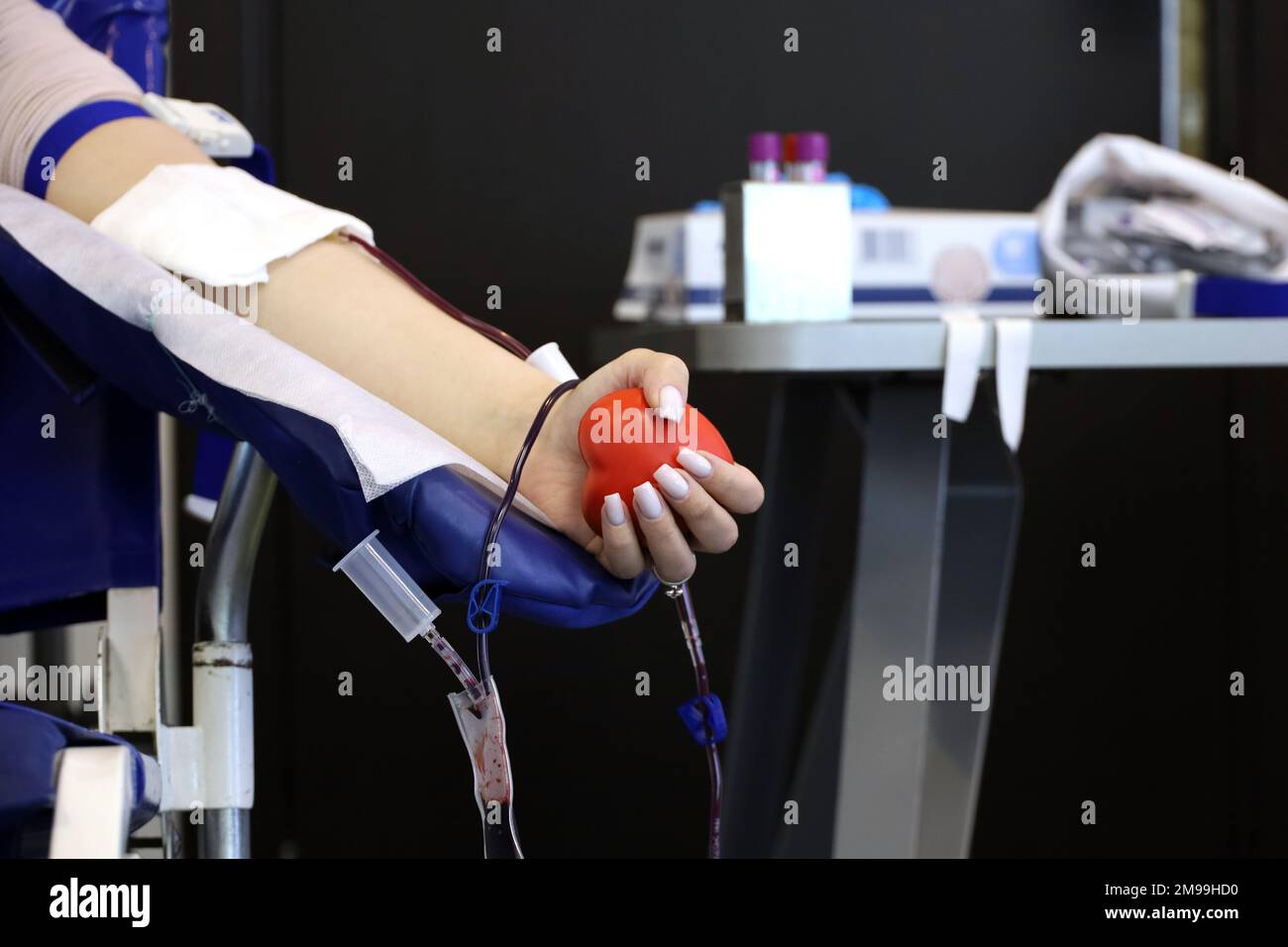 Woman blood donor in chair during donation with a blood bag and red ...
