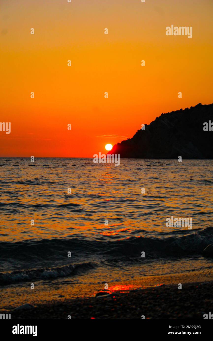 A vertical of the golden sunset shining brightly over the silhouettes ...