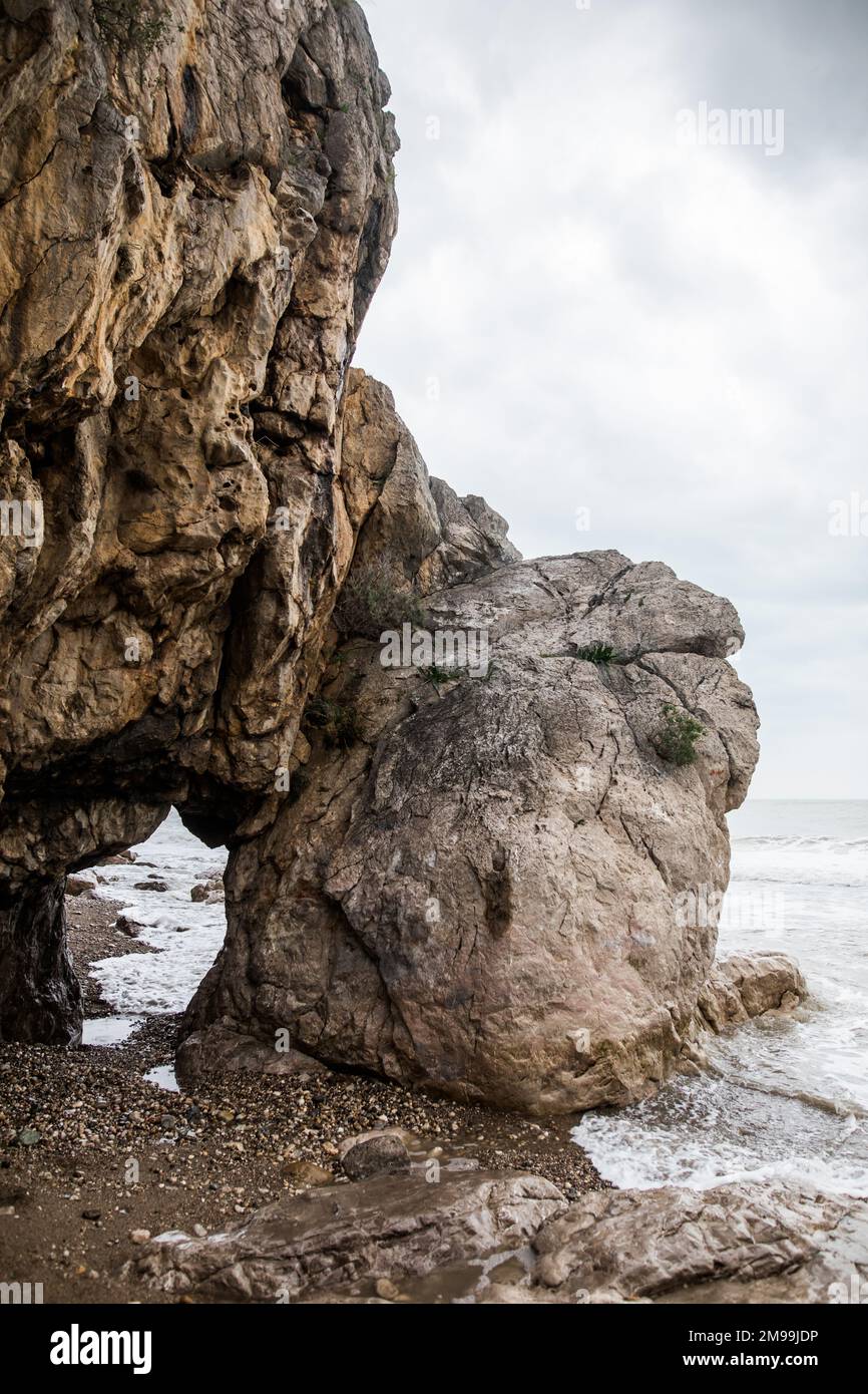 Some cliffs on the beach, at sea, with a hole in them Stock Photo - Alamy