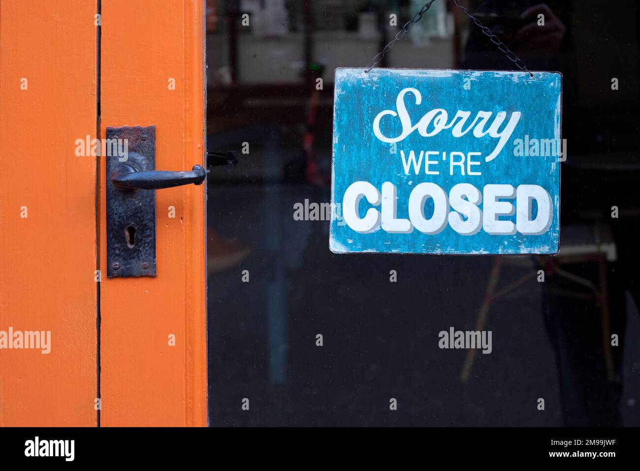 A Sorry we're closed sign clearly displayed on a shop doorway window ...