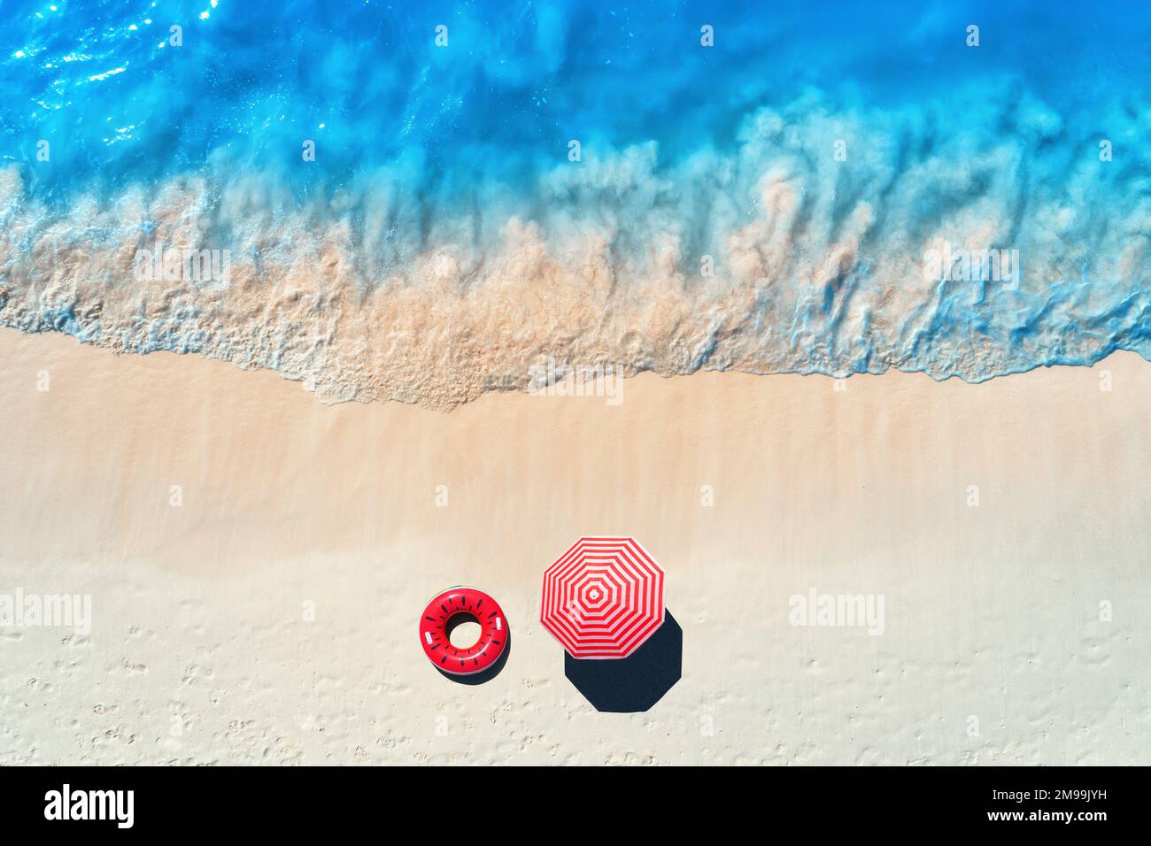 Sandy beach with red swim ring and umbrella at sunset. Top view Stock ...