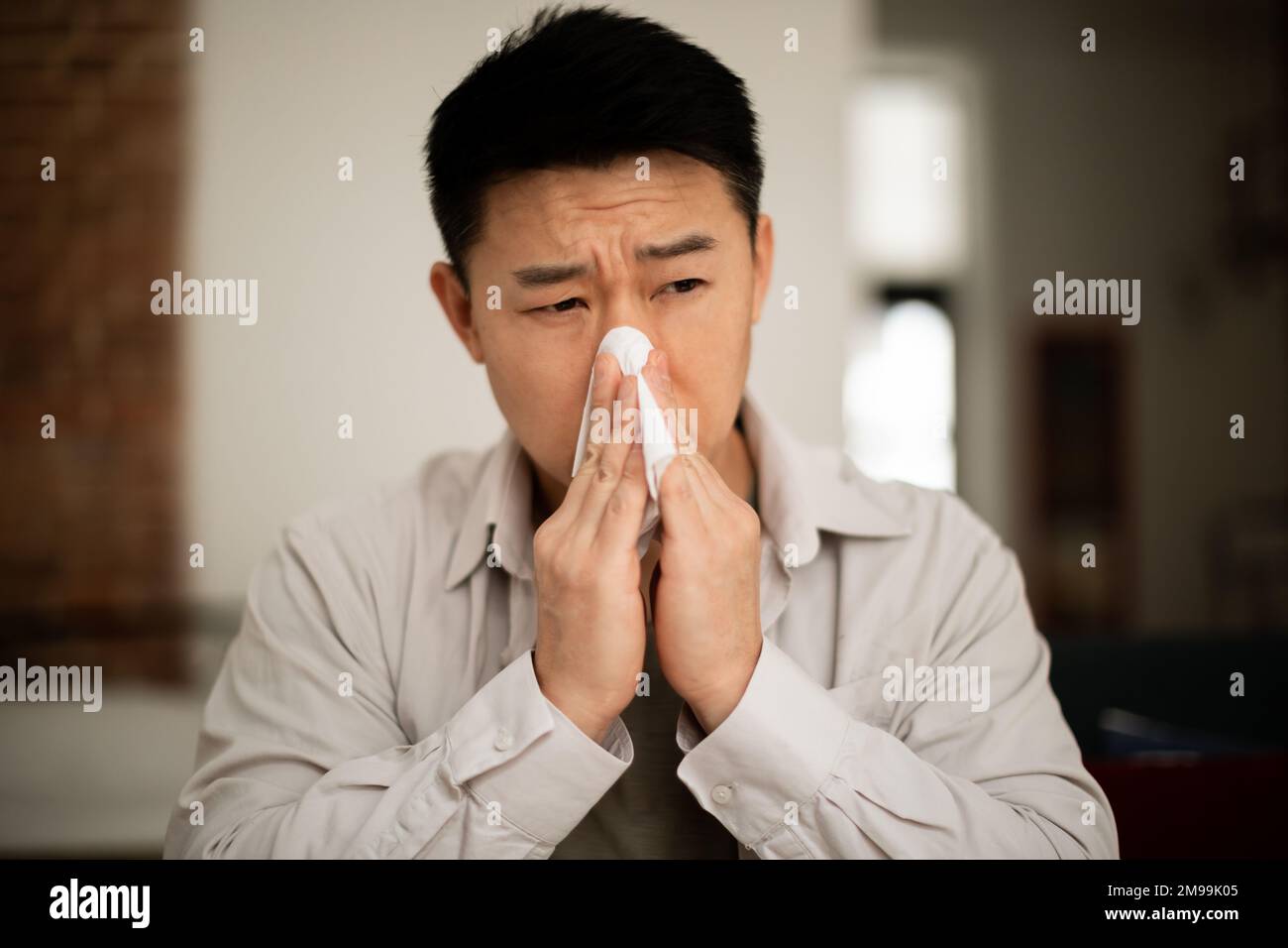 Unhappy middle aged asian man suffering from fever and flu, blowing ...