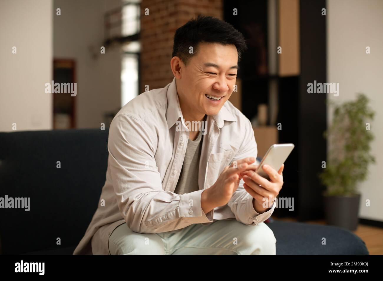 Happy korean middle aged man chatting on smartphone, surfing internet ...