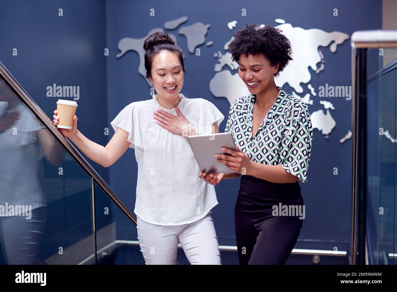 Female Colleagues With Digital Tablet Meeting On Stairs Of Office With ...