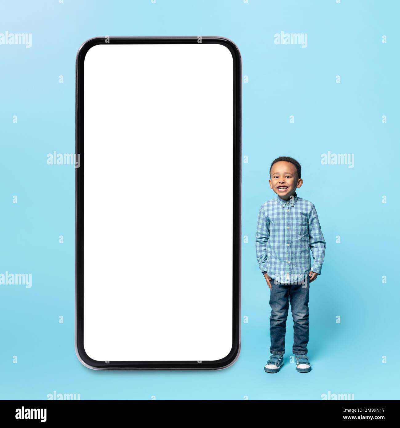 Kids content. Adorable little black boy standing near huge smartphone ...