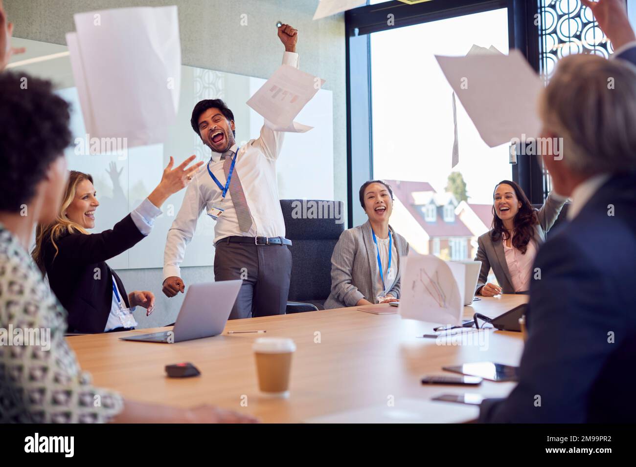 Multi-Cultural Business Team Celebrating Deal Around Table In Office ...