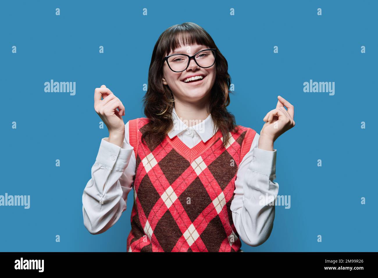 Young female student in glasses having fun on blue background Stock ...