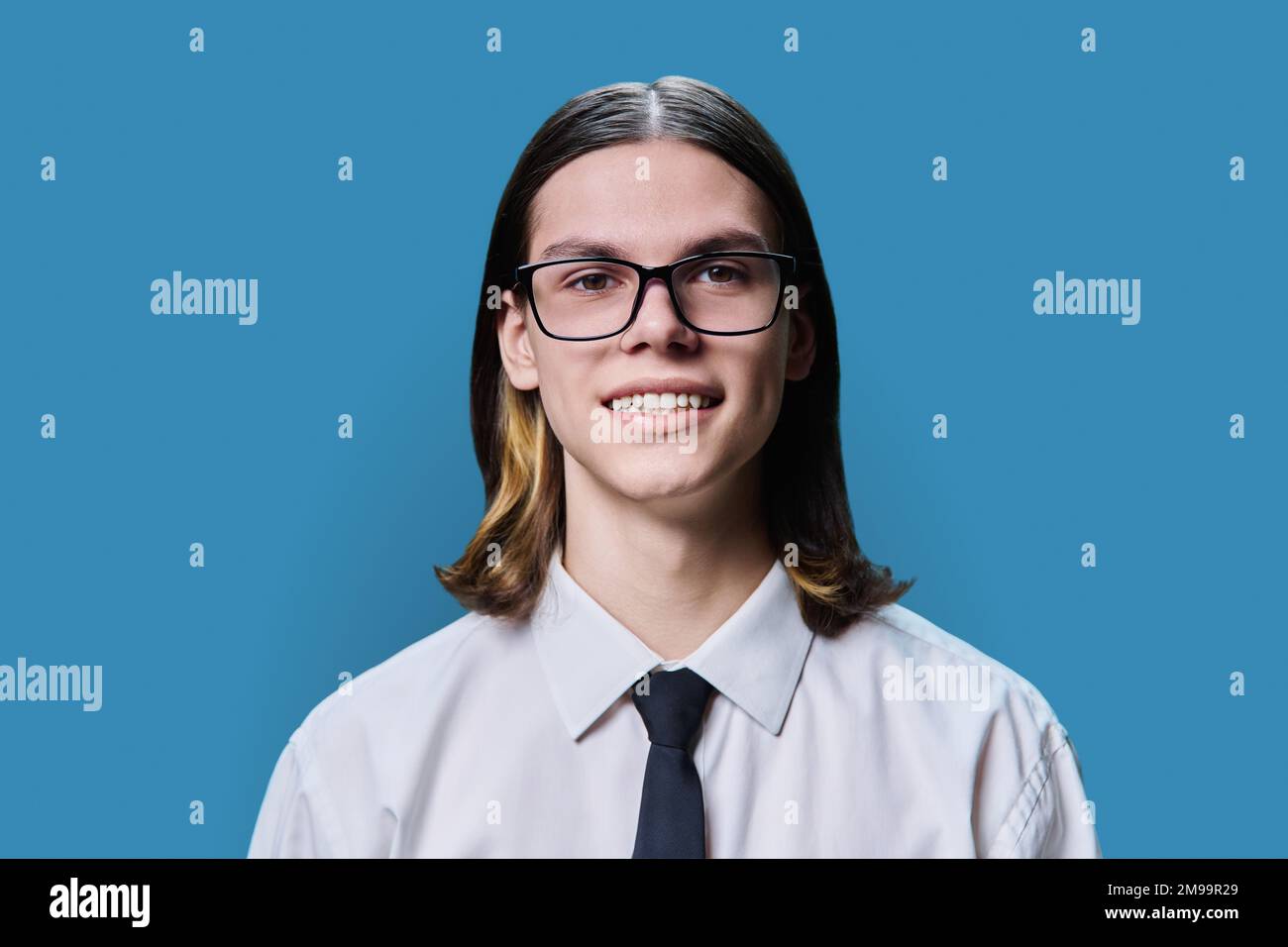 Headshot portrait of smiling teenage guy on blue studio background ...