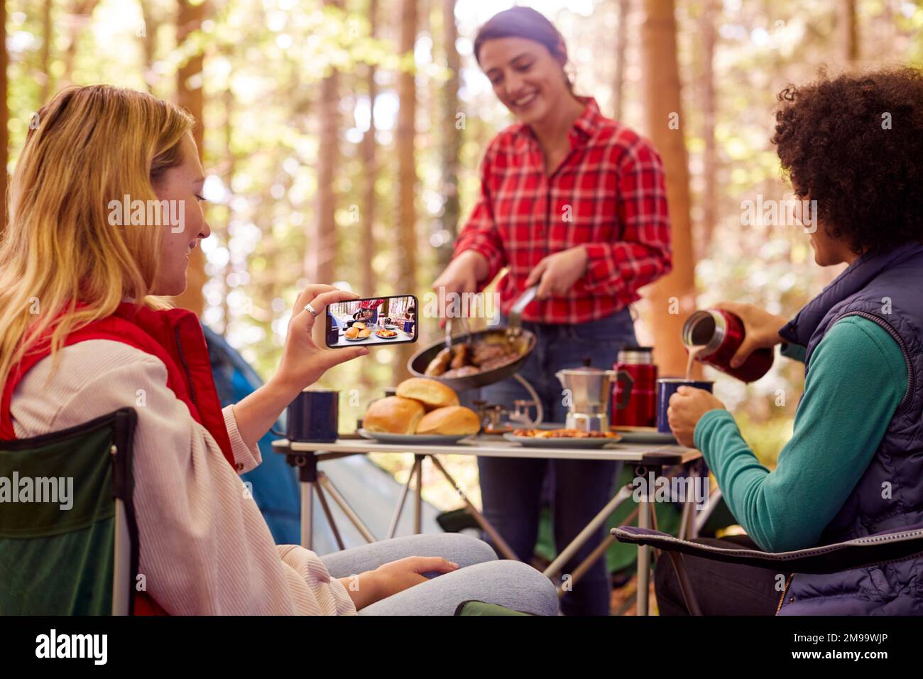 Woman Taking Photo Of Food As Female Friends On Camping Holiday In ...