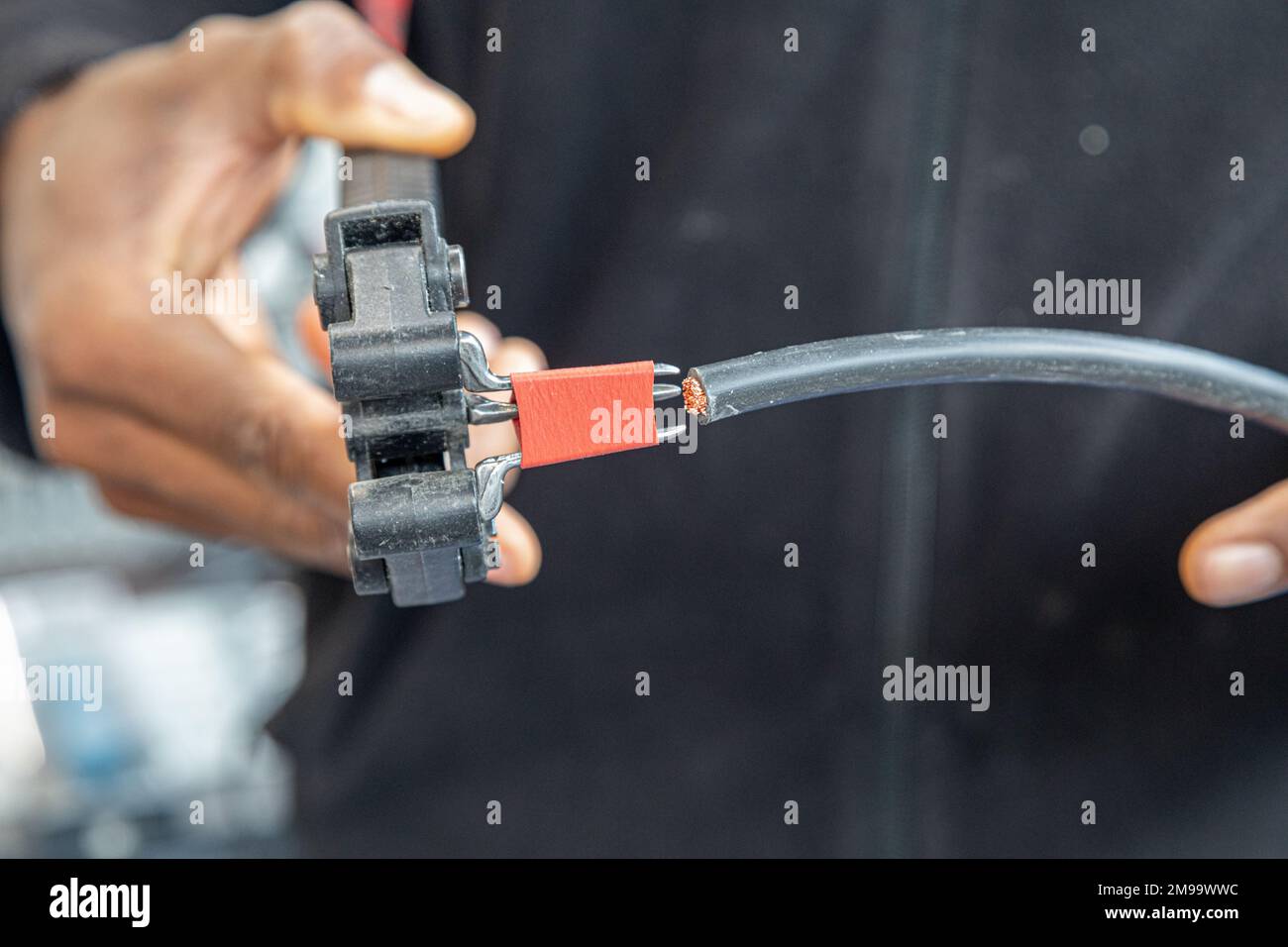 A closeup of worker hands inserting a red insulating sleeve to identify ...