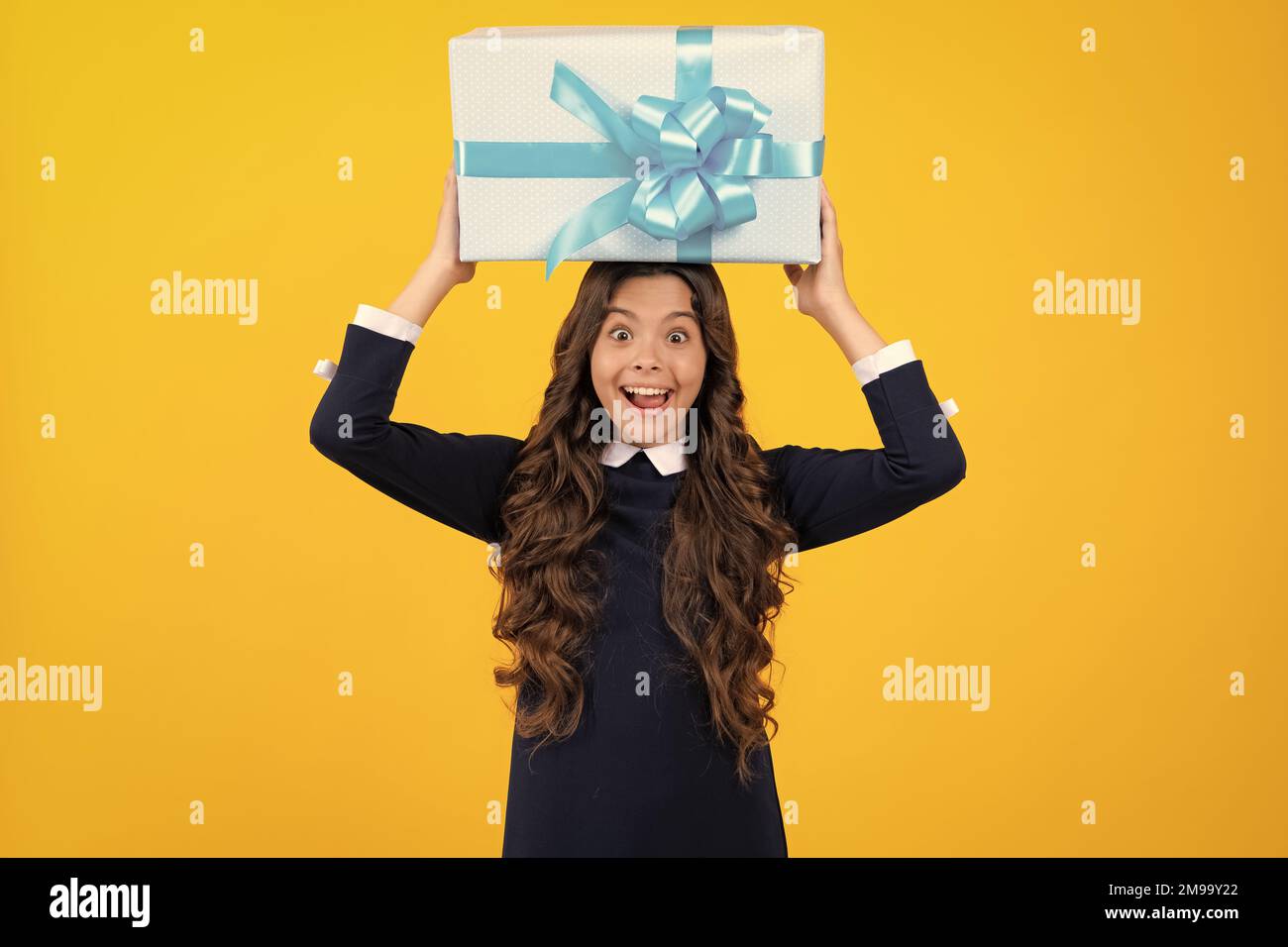 Excited face. Child with gift present box on isolated studio background ...
