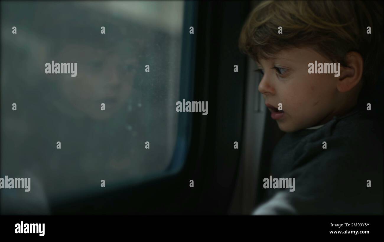 Little boy traveling by train staring outside through train window ...