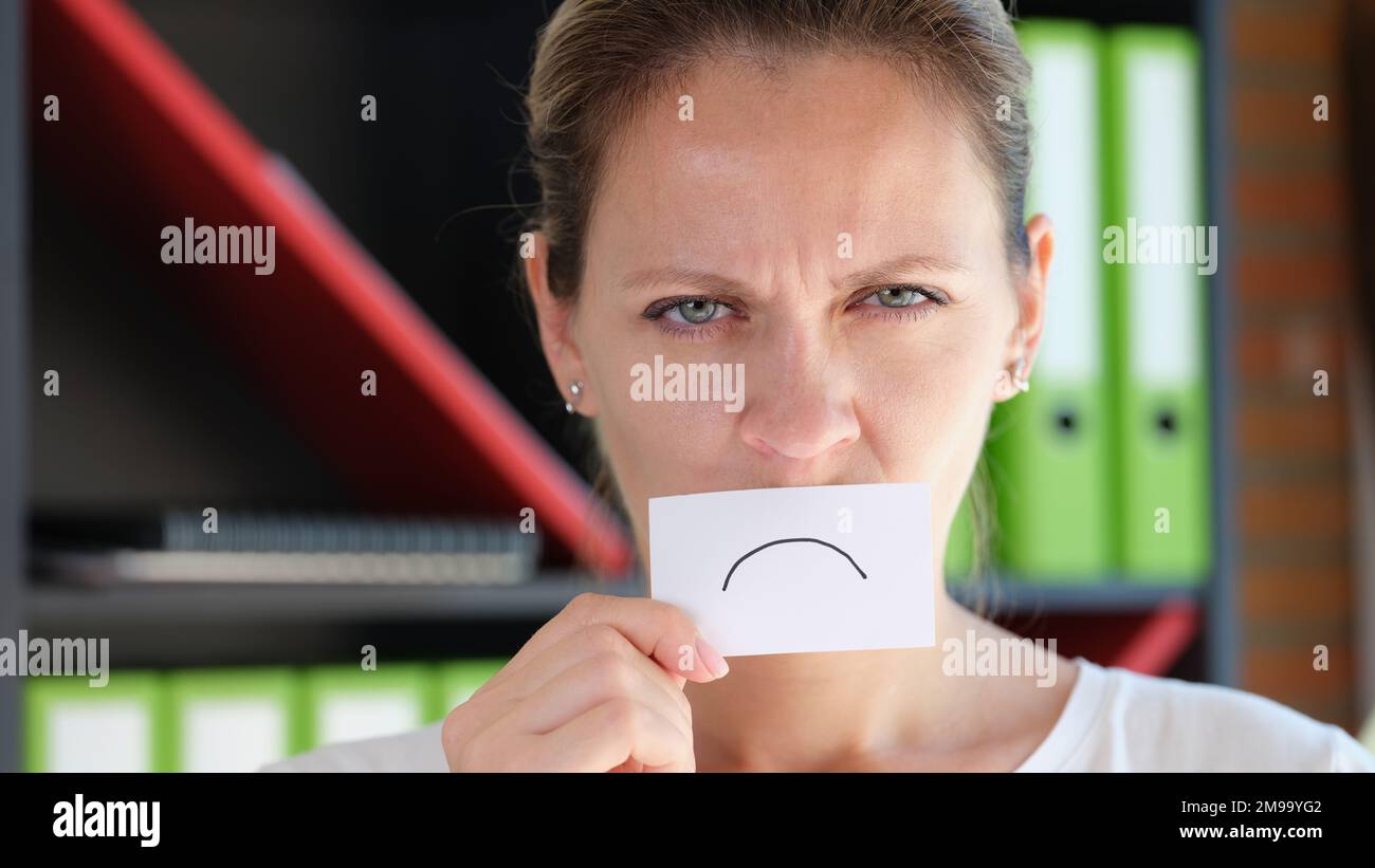 Unhappy woman in office holds paper with sad emotion in front of her ...