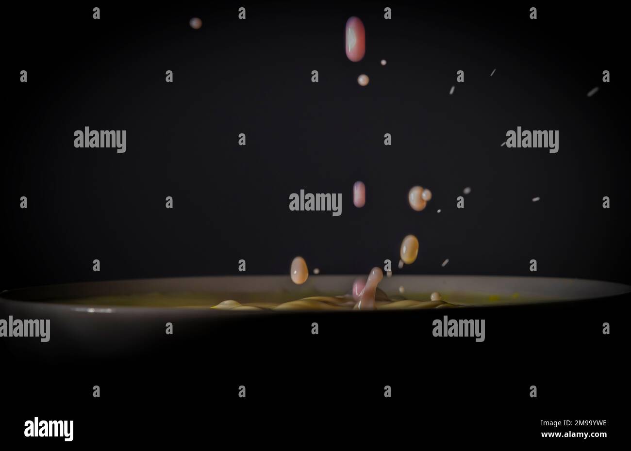 Color fresh sweet milk drops into another color of milk in cup with ...