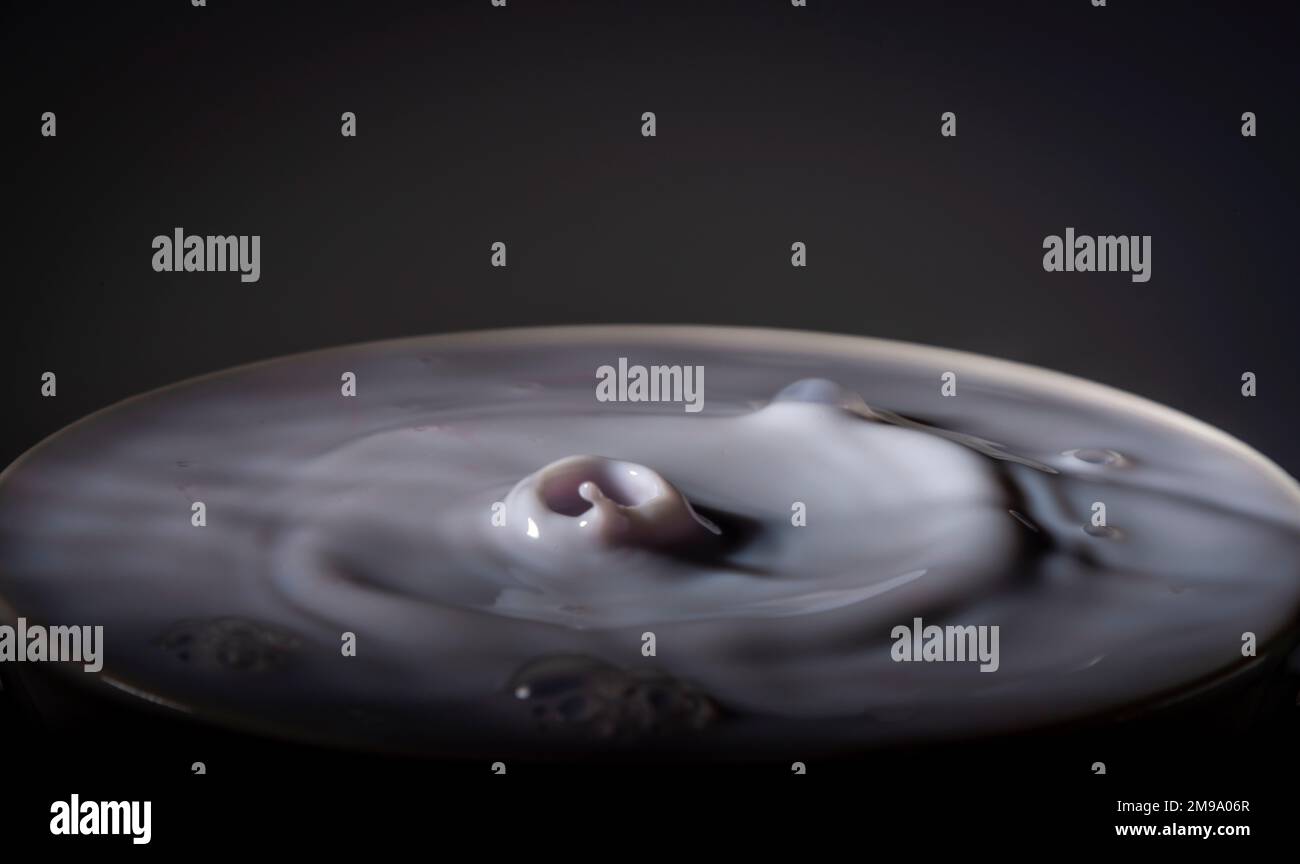 Color fresh sweet milk drops into another color of milk in cup with ...