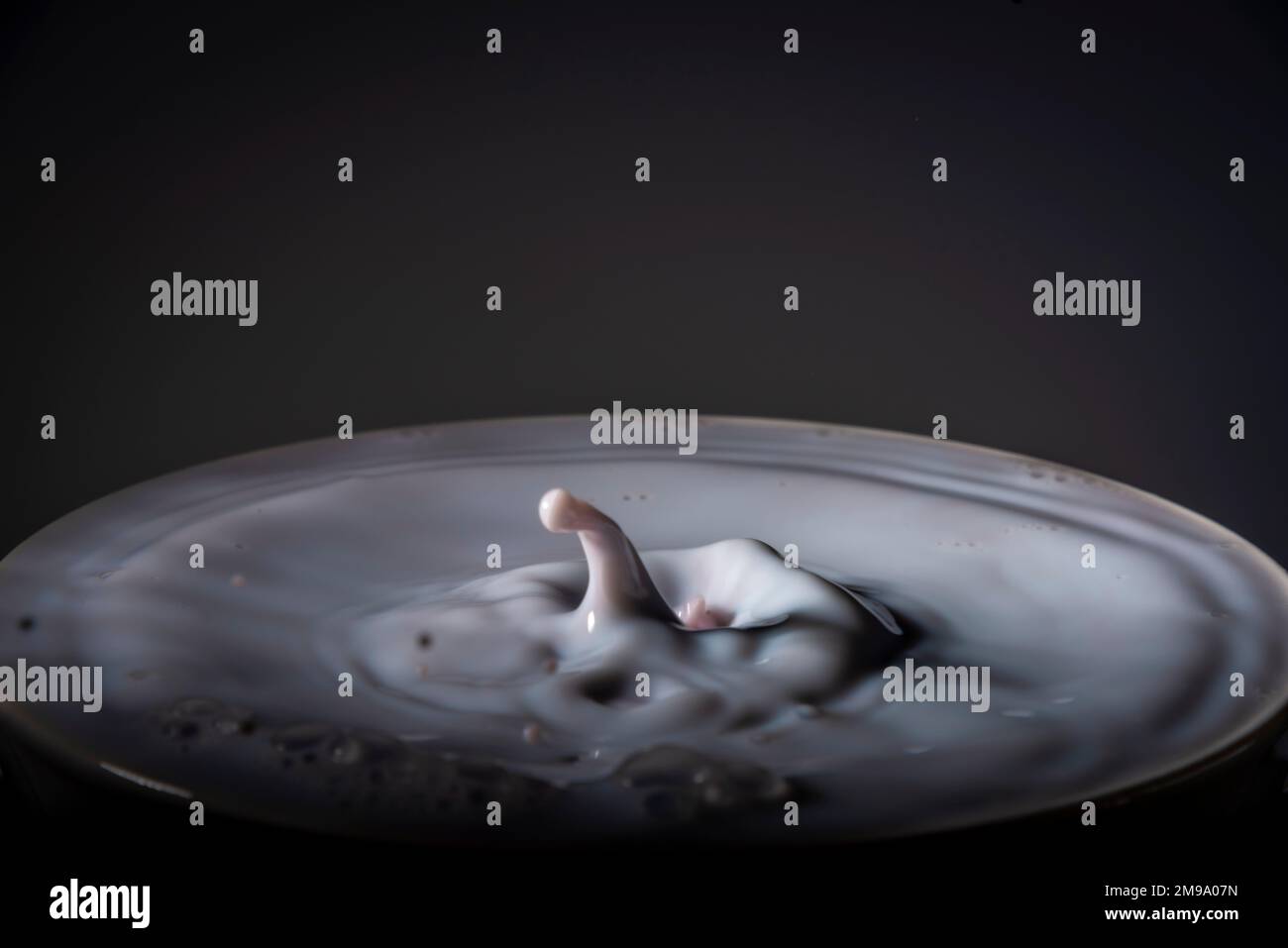 Color fresh sweet milk drops into another color of milk in cup with ...