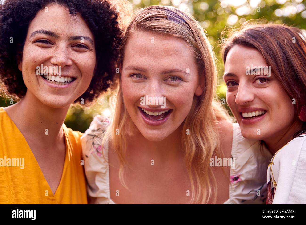 Portrait Of Three Female Friends Sitting Outdoors Together And Catching ...