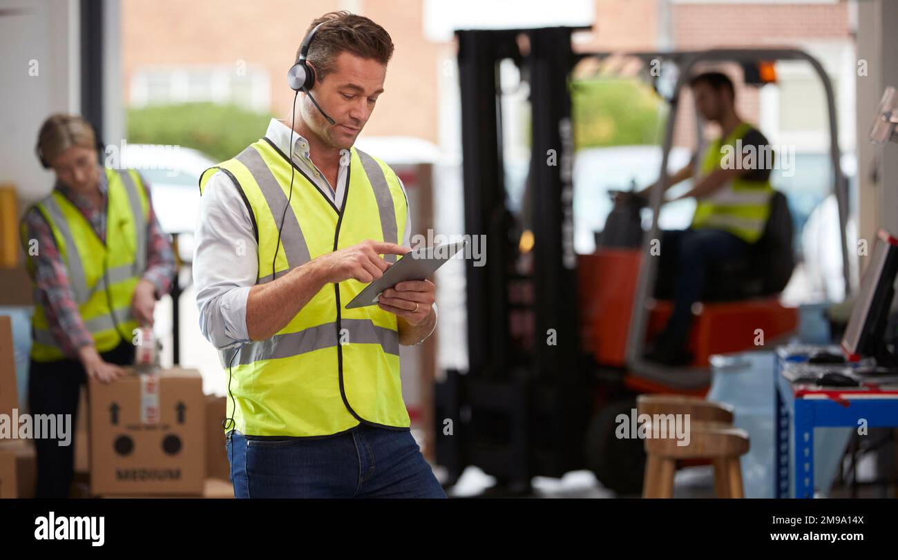 Male Worker Wearing Headset In Logistics Distribution Warehouse Using ...