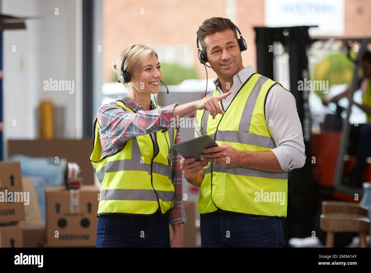 Male And Female Workers Wearing Headsets In Logistics Distribution ...