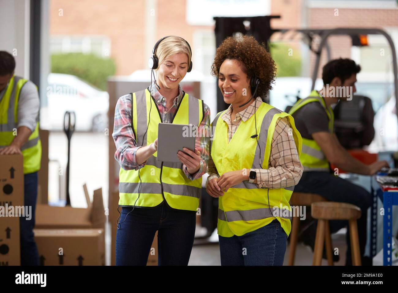 Two Female Workers Wearing Headsets In Logistics Distribution Warehouse ...