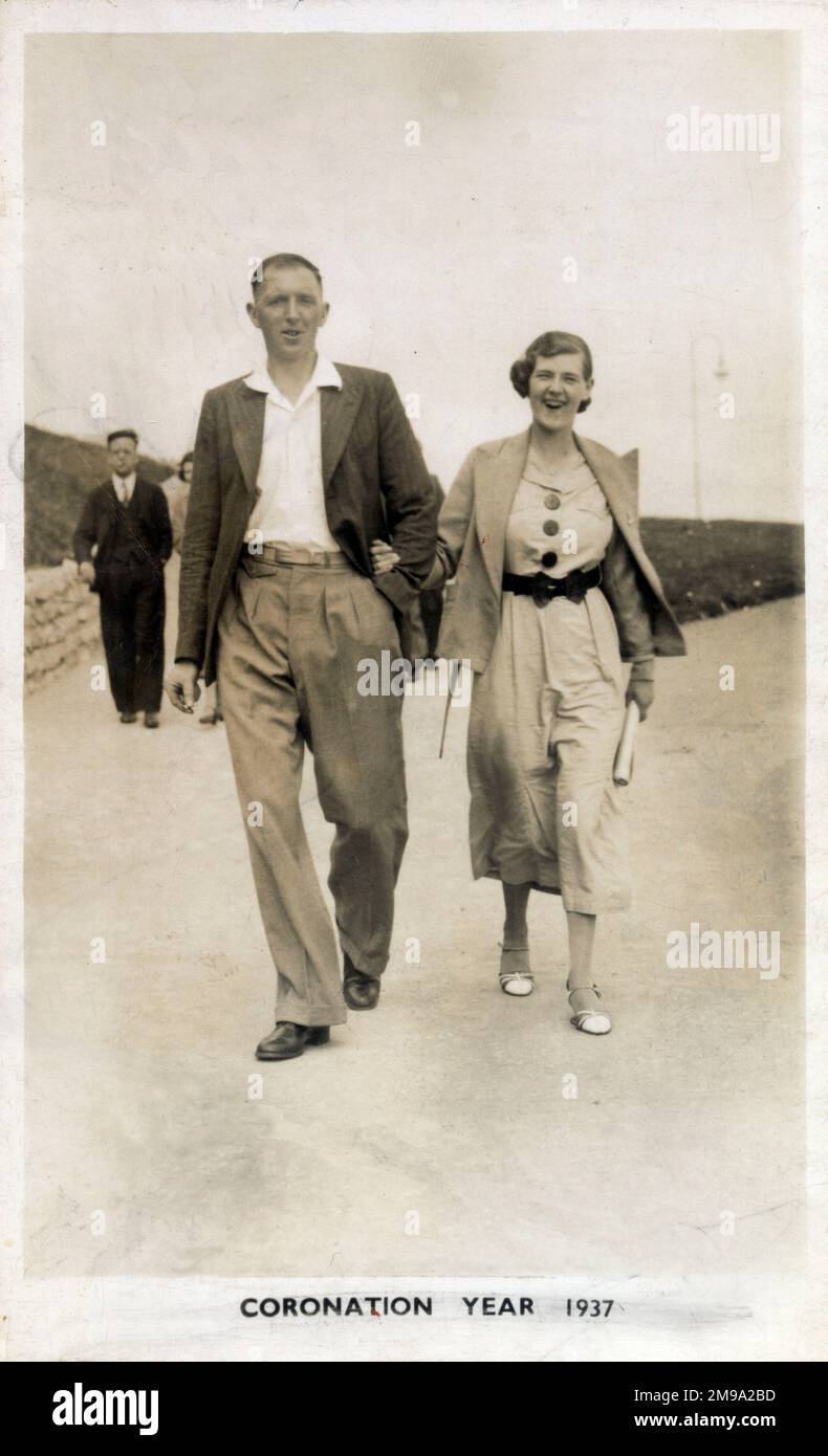A jolly young couple strolling along the seafront at Bridlington, East ...