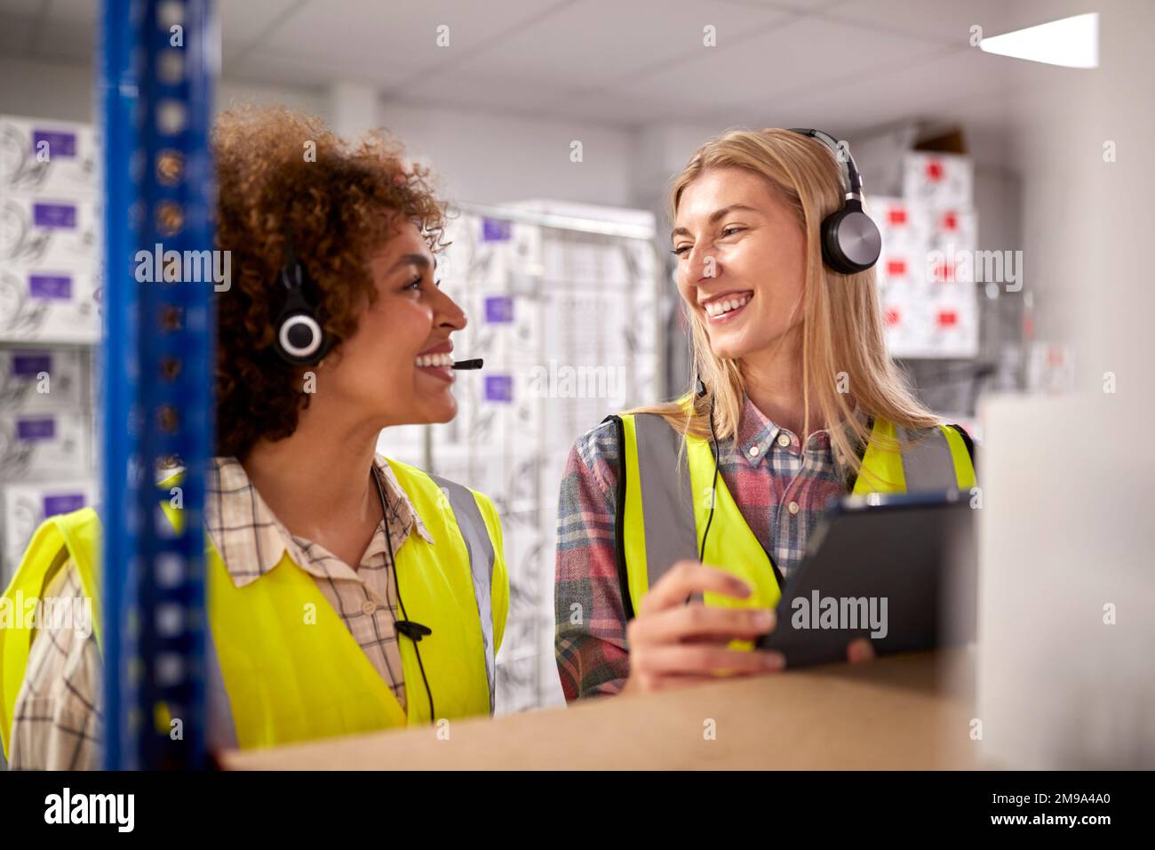 Two Female Workers Wearing Headsets In Logistics Distribution Warehouse ...