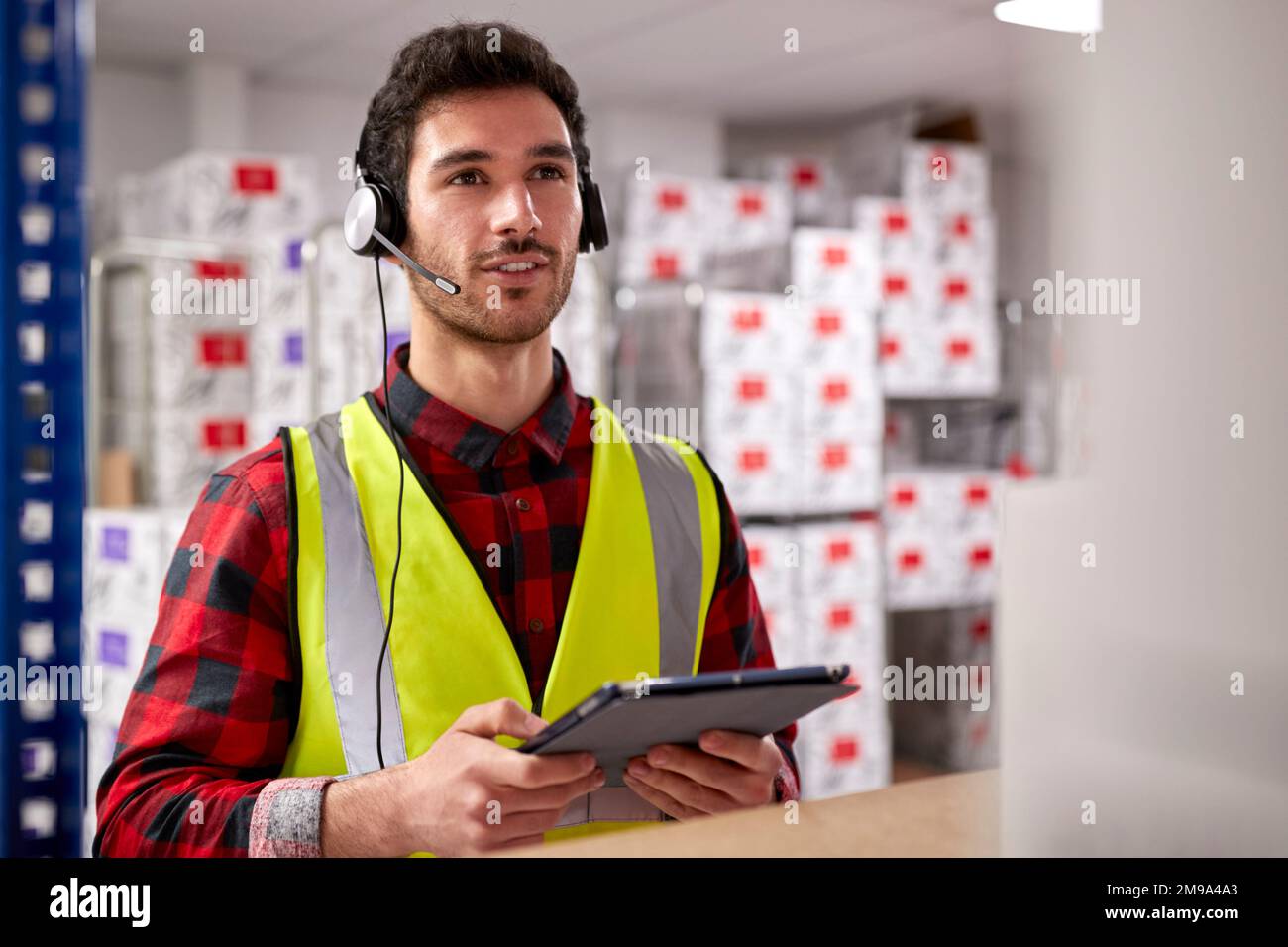 Male Worker Wearing Headset In Logistics Distribution Warehouse Using ...