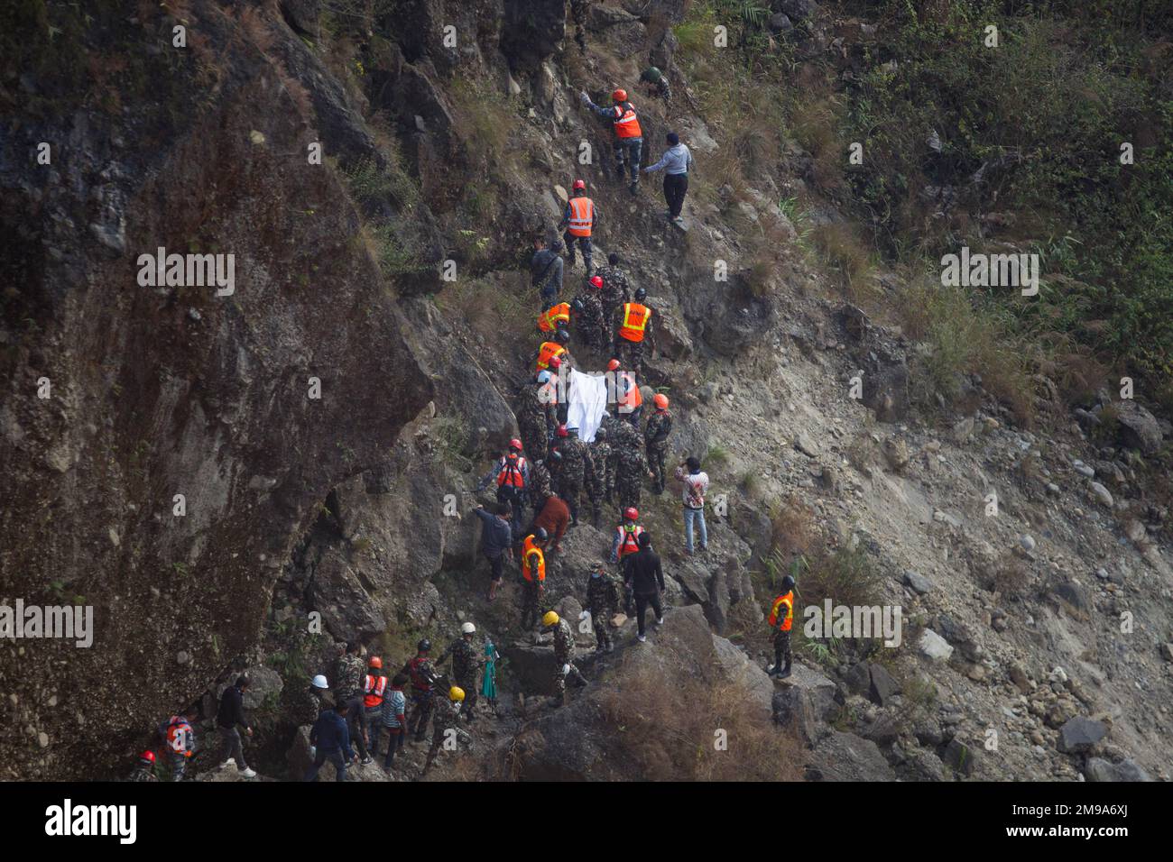 Pokhara, Nepal. 17th Jan, 2023. Rescuers carry a body at the crash site ...