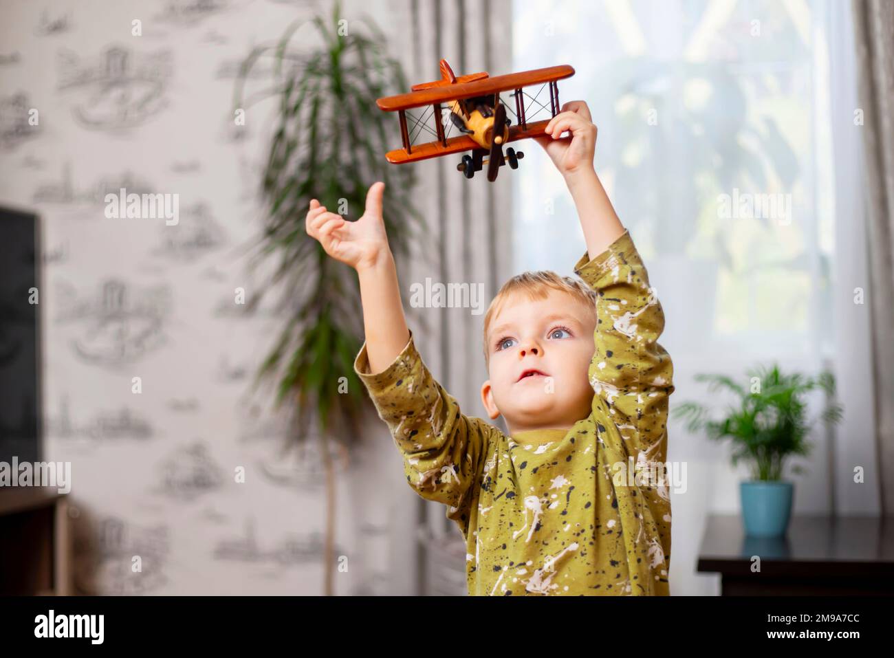 Happy child boy plays with toy airplane and dreams of becoming a pilot ...