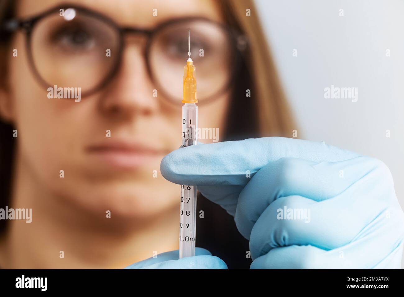 Doctor in glasses and gloves preparing syringe for injection Stock ...