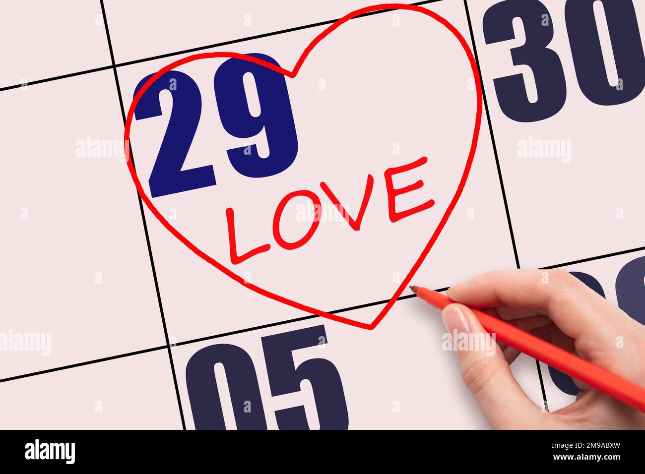 29th day of the month. Hand writing text LOVE and drawing a red heart ...