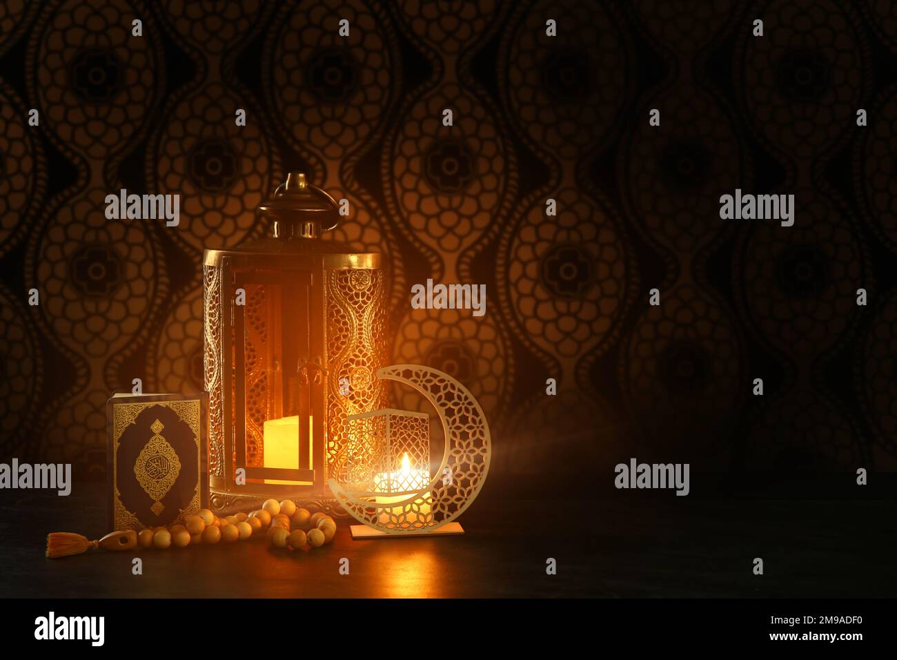 Glowing candles with Muslim lamp, Quran and tasbih on dark background ...