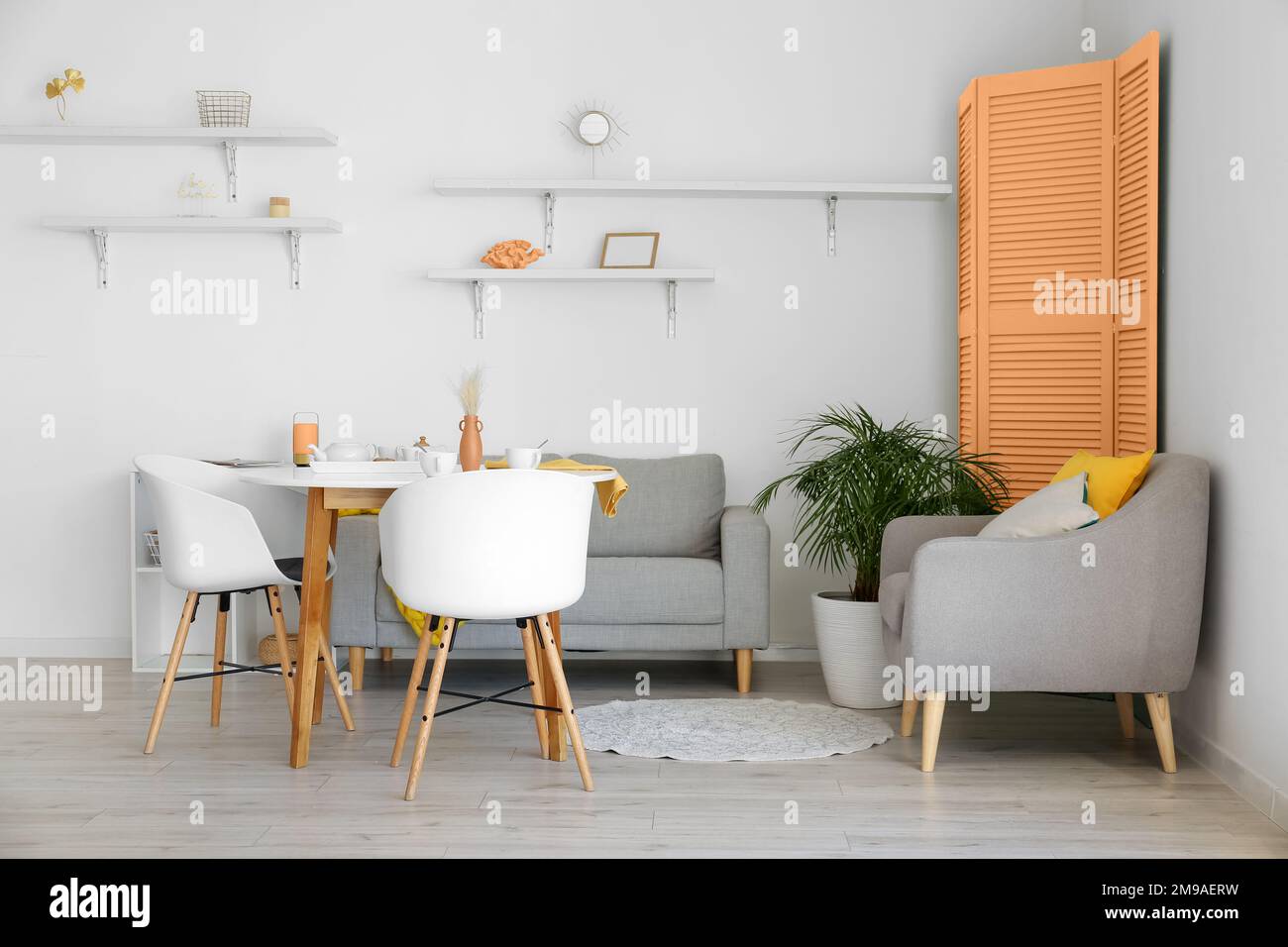 Interior of light dining room with table, grey furniture and orange ...