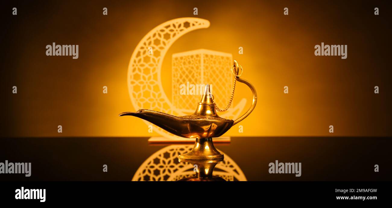 Aladdin lamp of wishes and decorative crescent on table against dark ...